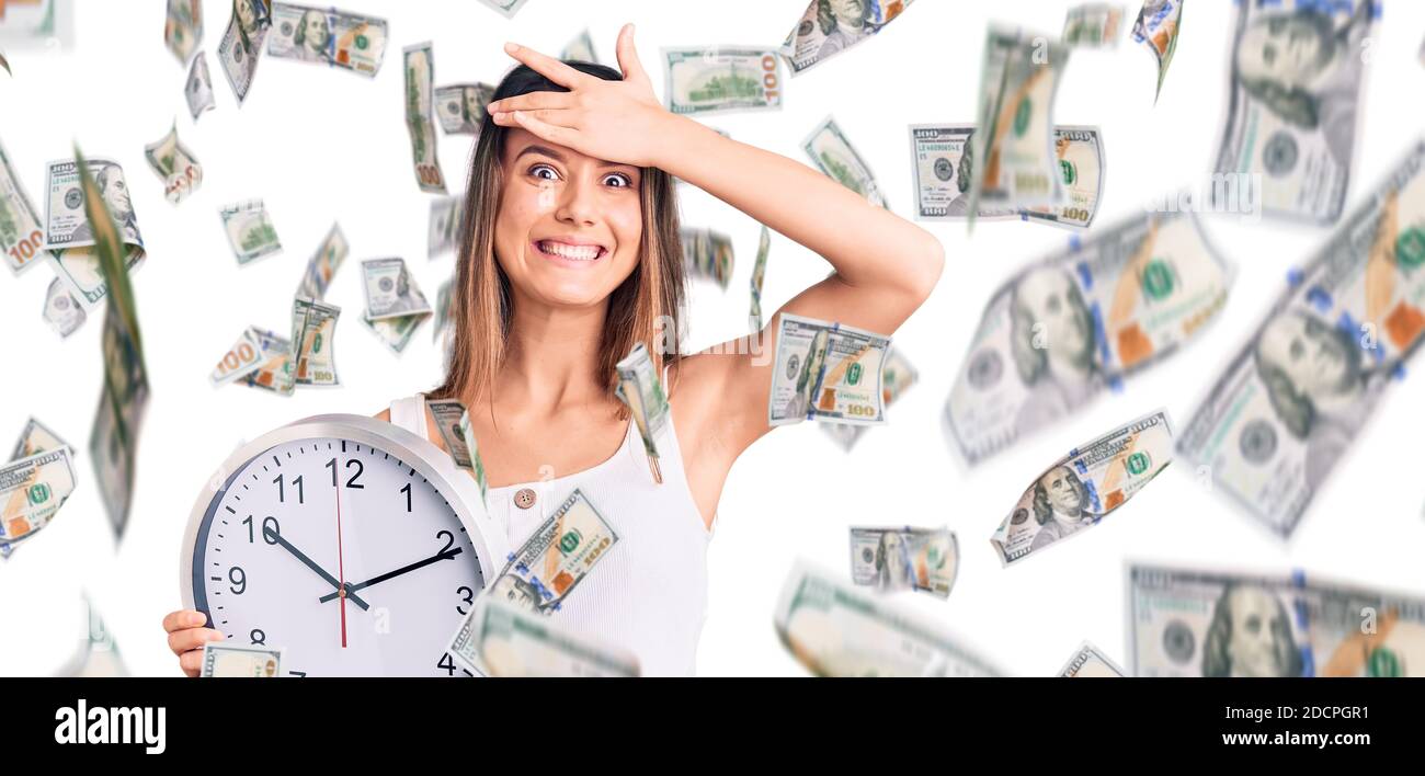 Young beautiful girl holding big clock stressed and frustrated with ...