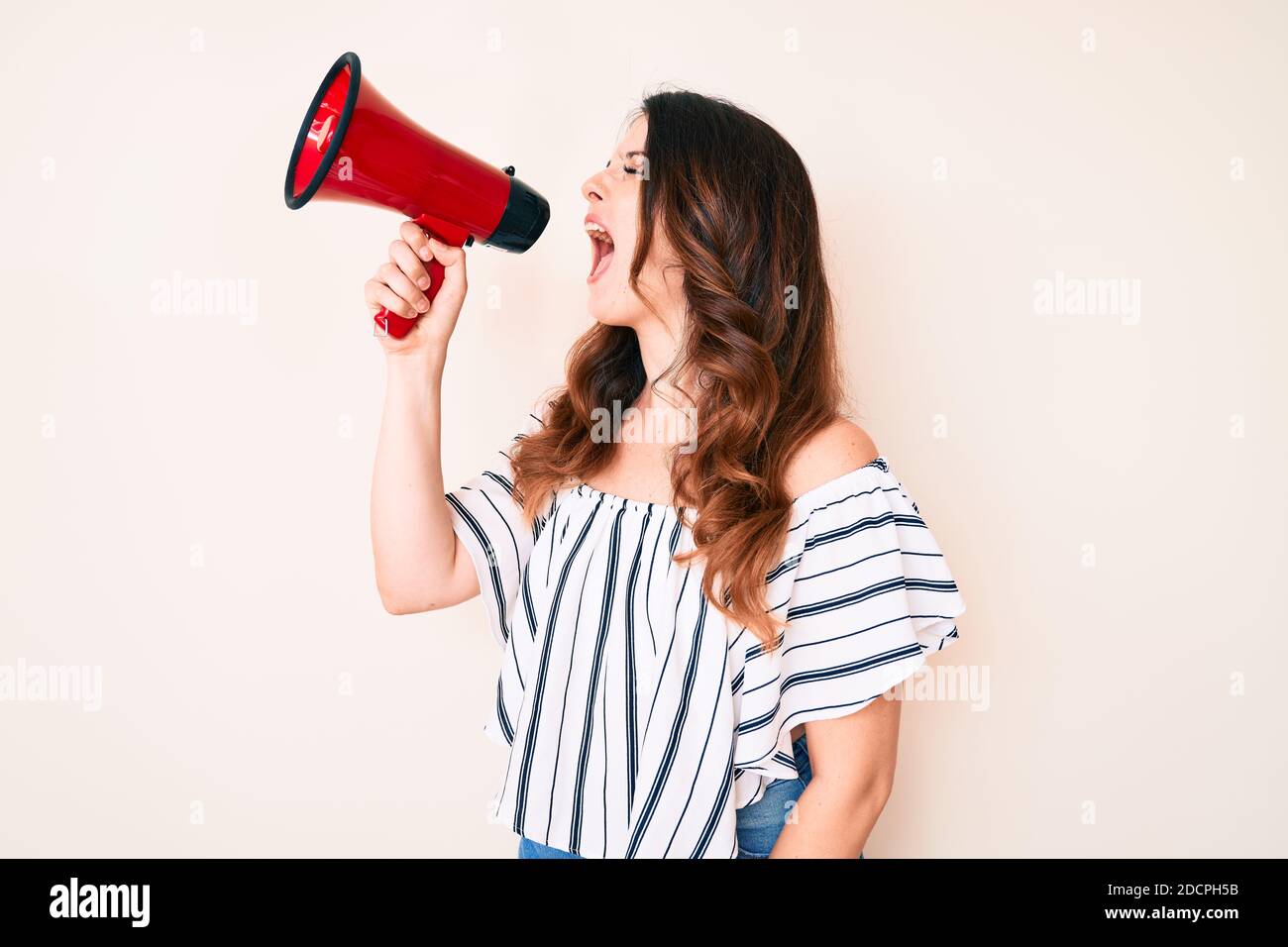 Young woman shouting exited throung megaphone, yelling and screaming ...