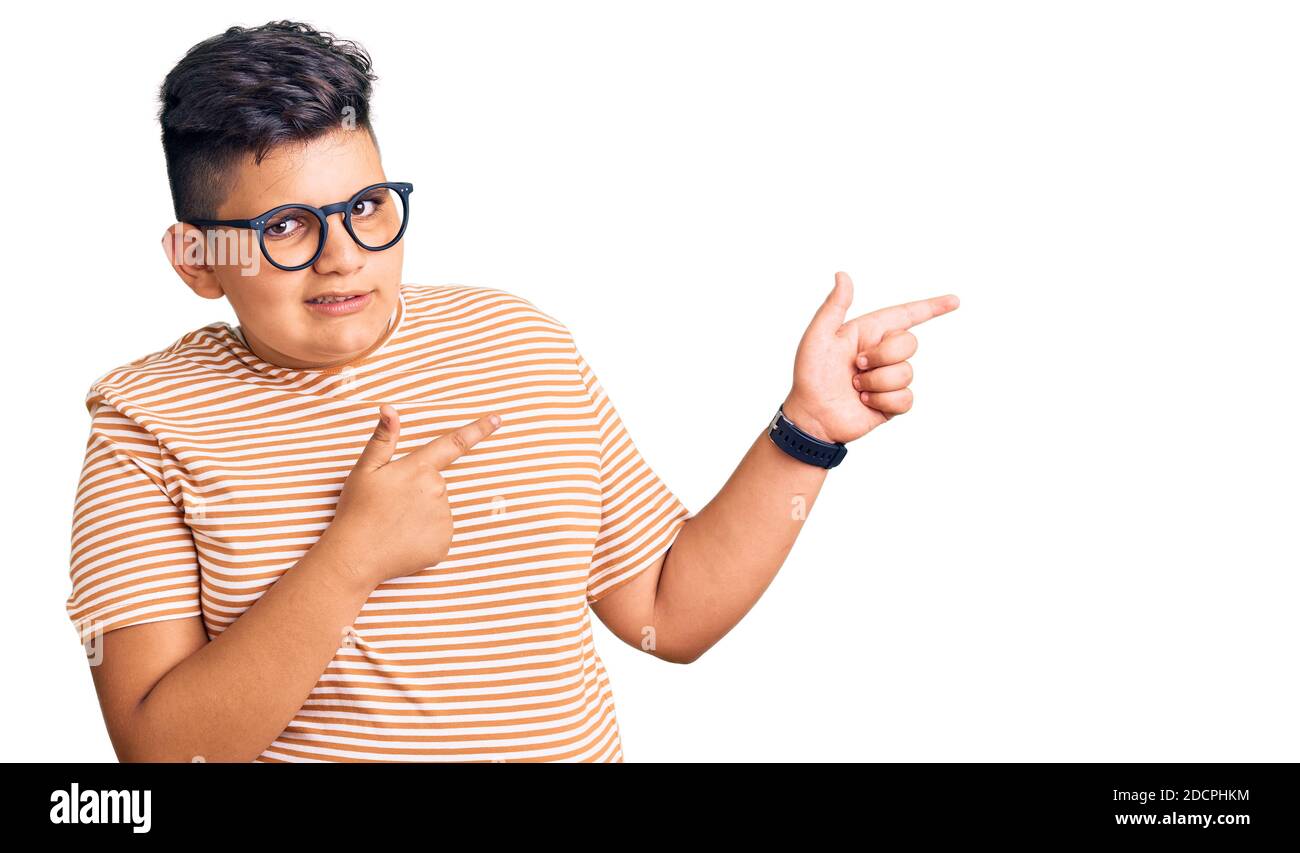 Little boy kid wearing casual clothes and glasses pointing aside ...