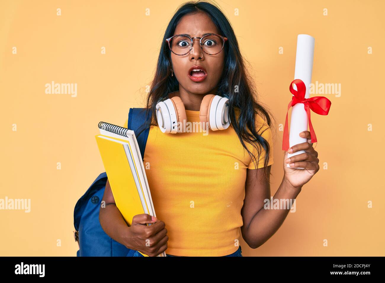 Young indian girl wearing student backpack holding diploma clueless and ...
