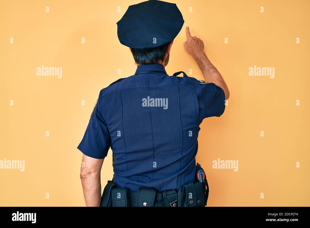 Middle age hispanic man wearing police uniform posing backwards ...