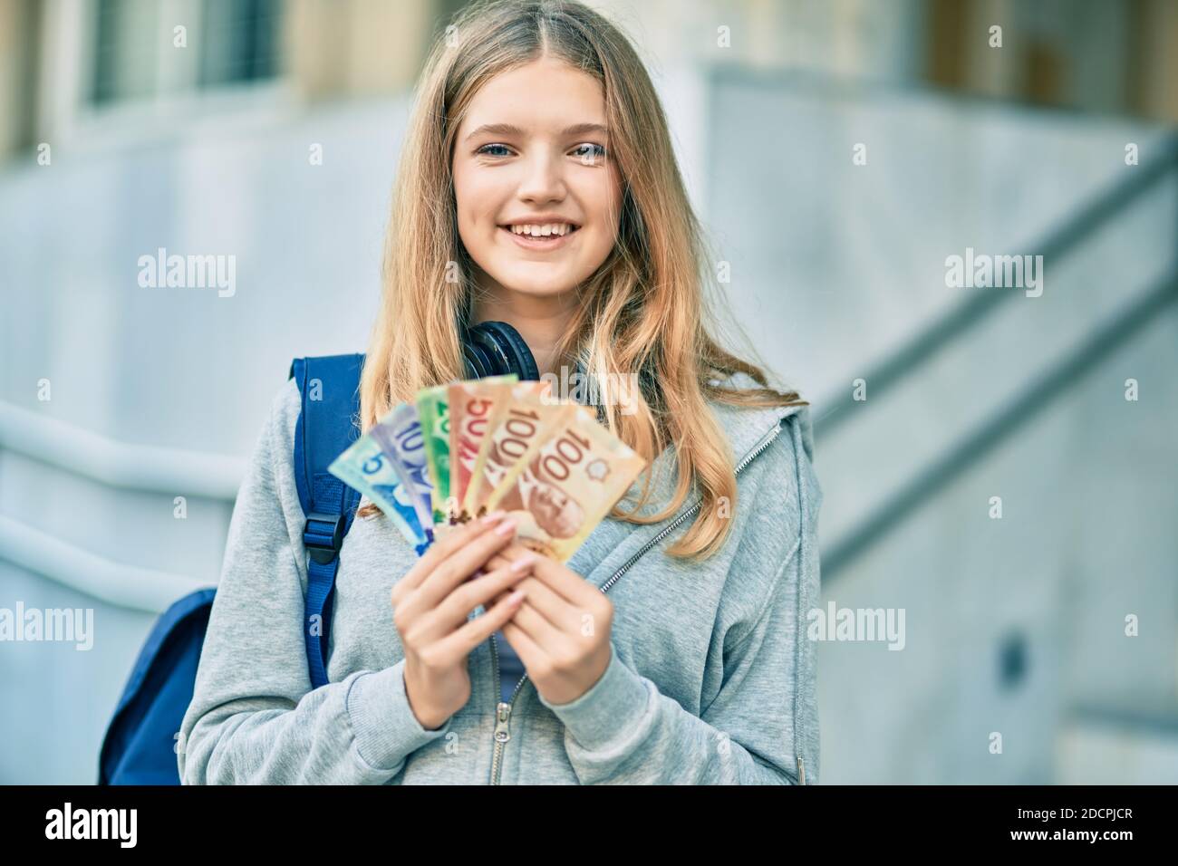 Beautiful caucasian student teenager using headphones holding canadian ...