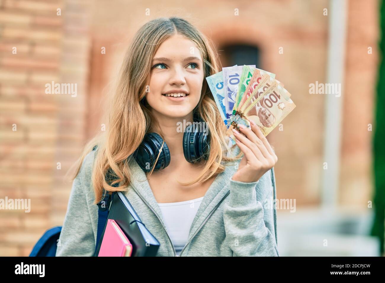 Beautiful caucasian student teenager using headphones holding canadian ...