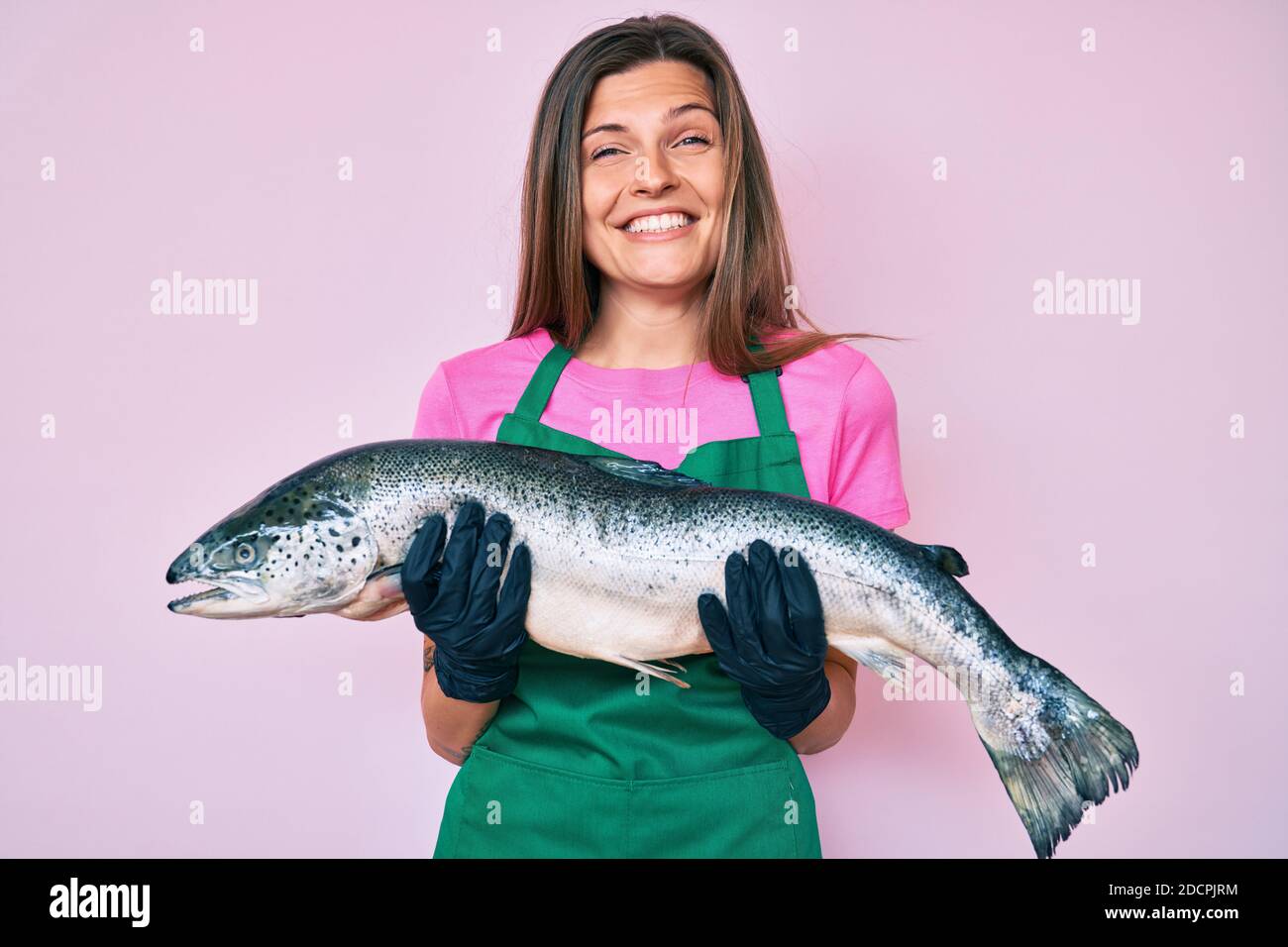 Beautiful caucasian woman fishmonger selling fresh raw salmon smiling ...