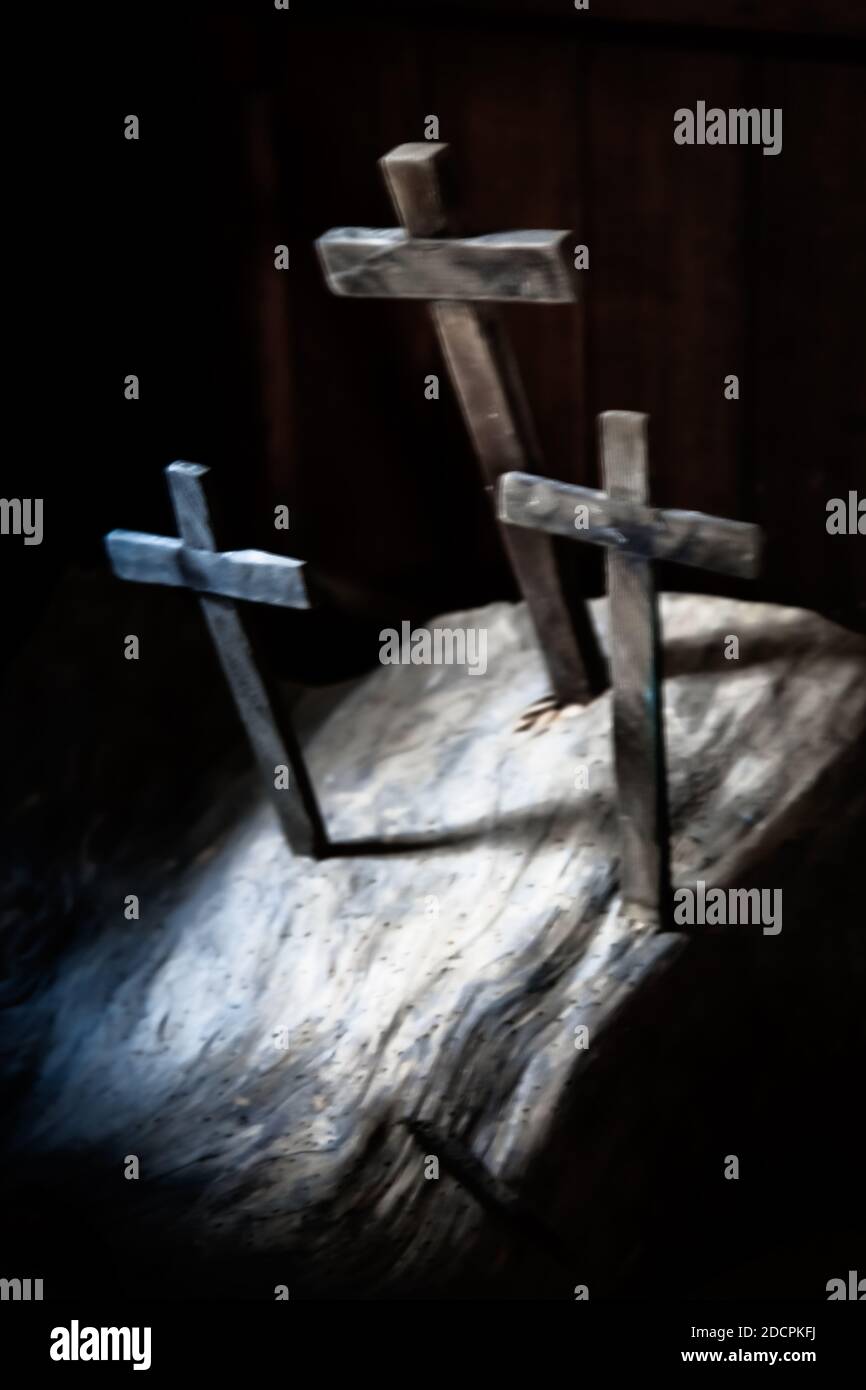 A blurry view of Three Wooden Crosses stabbed into a slab in a trinity ...