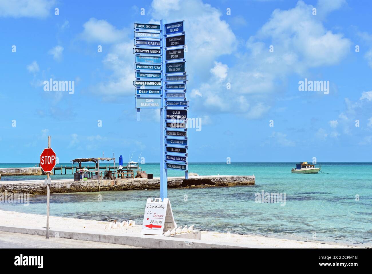 A red stop sign and a large signpost along the edge of a white sand ...