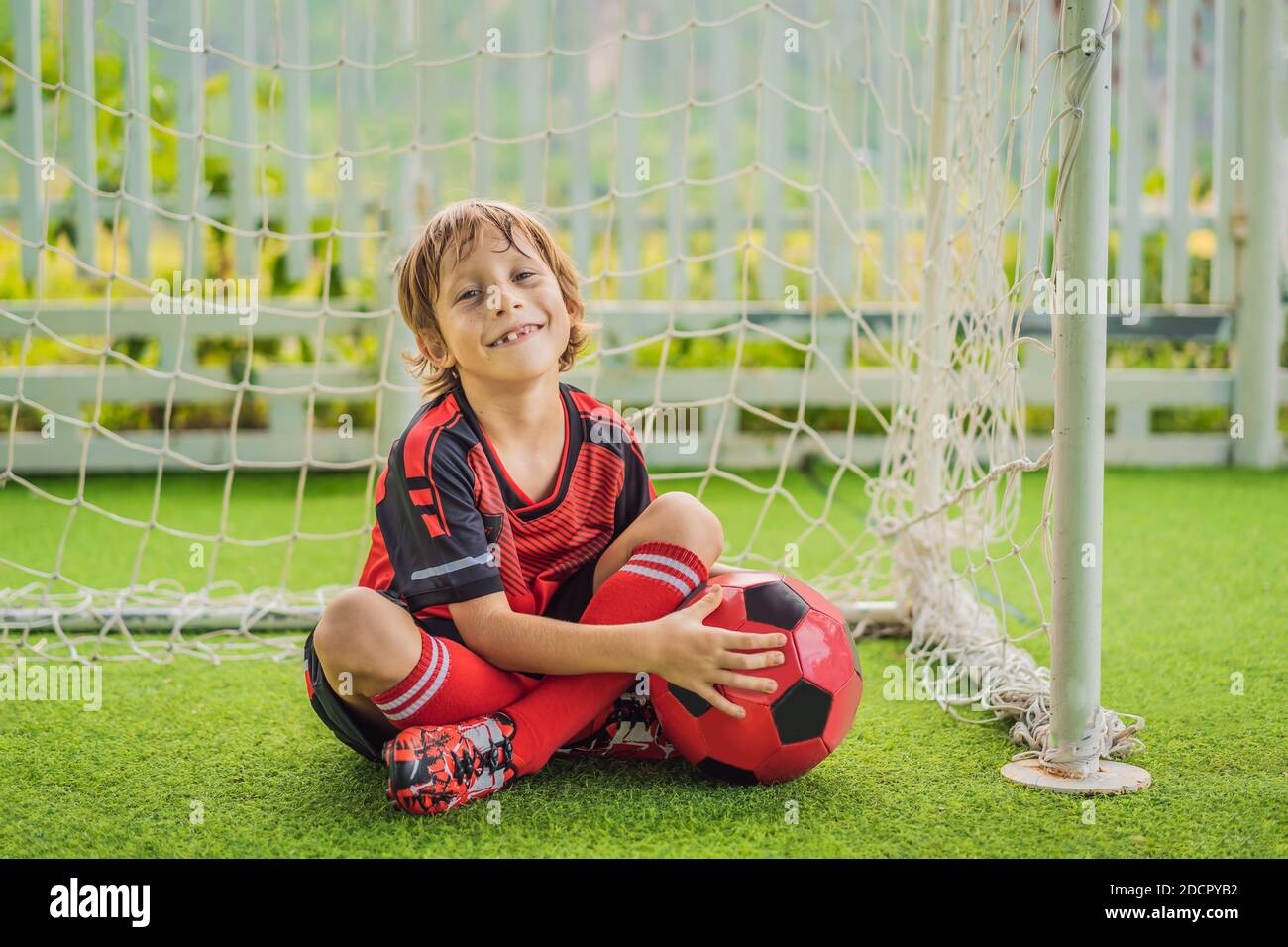 Little cute kid boy in red football uniform playing soccer, football on ...