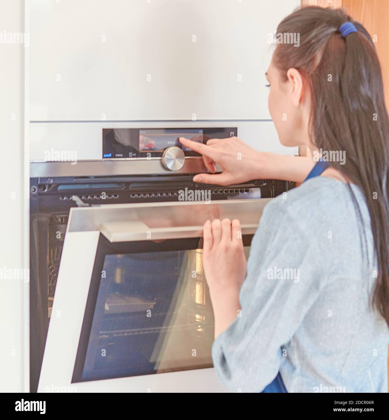 Beautiful woman in the kitchen, waiting with the front of the oven ...