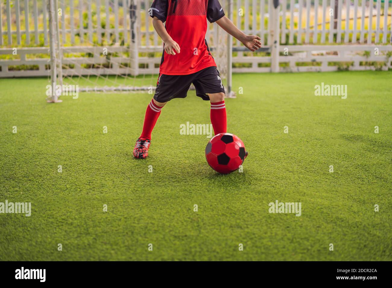 Little cute kid boy in red football uniform playing soccer, football on ...