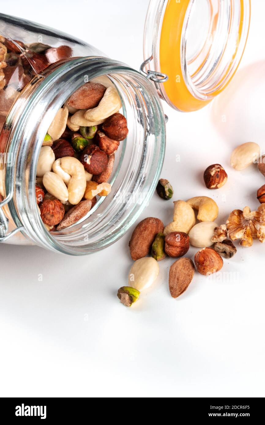 A variety of nuts in a mason jar, on a white background with copy space ...