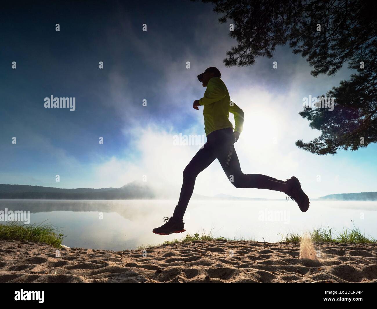 Tall slim runner on sandy beay along lake. Healthy and active lifestyle ...