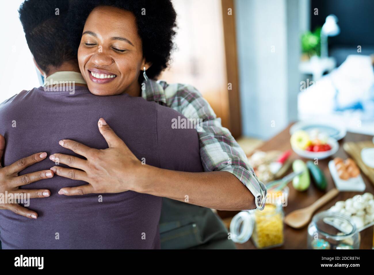 Beautiful couple are hugging and smiling while spending time in kitchen ...