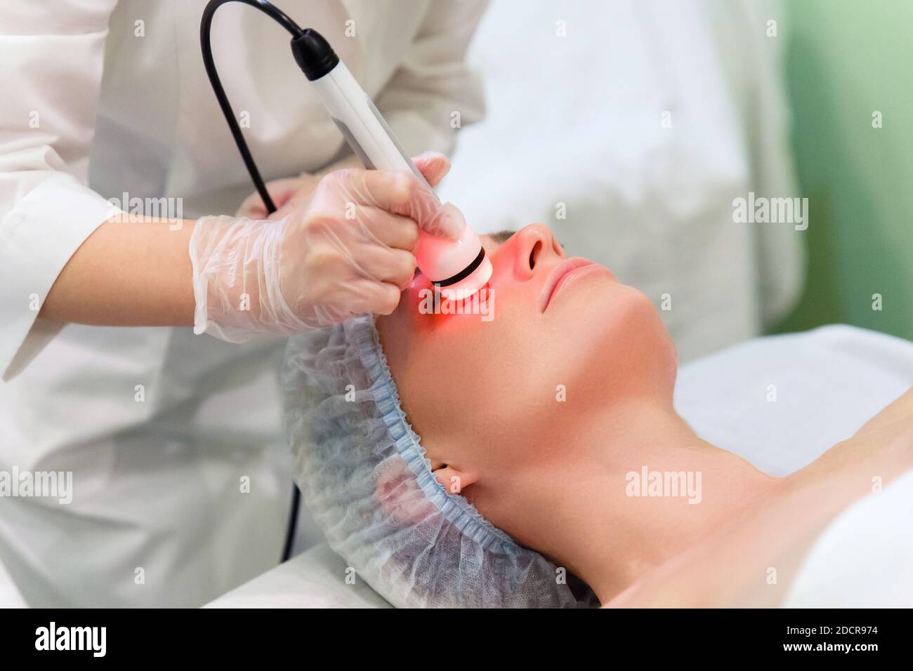 A young woman in a spa salon is having a face lift. The beautician ...