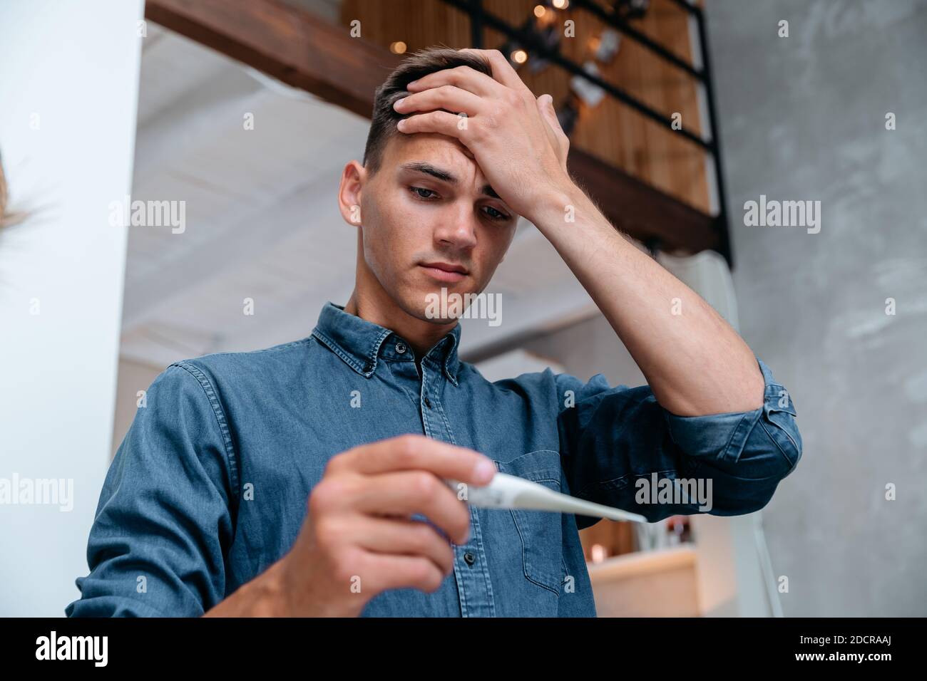 young man looking at the digital thermometer reading Stock Photo - Alamy