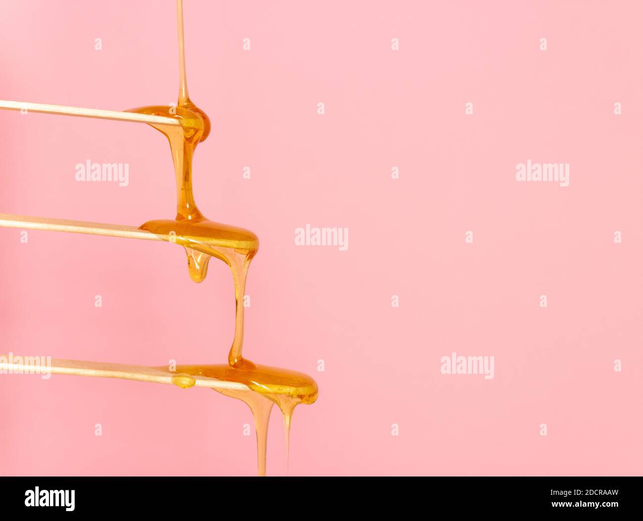 Sugar paste for hair removal runs down a wooden spatula. The concept of ...