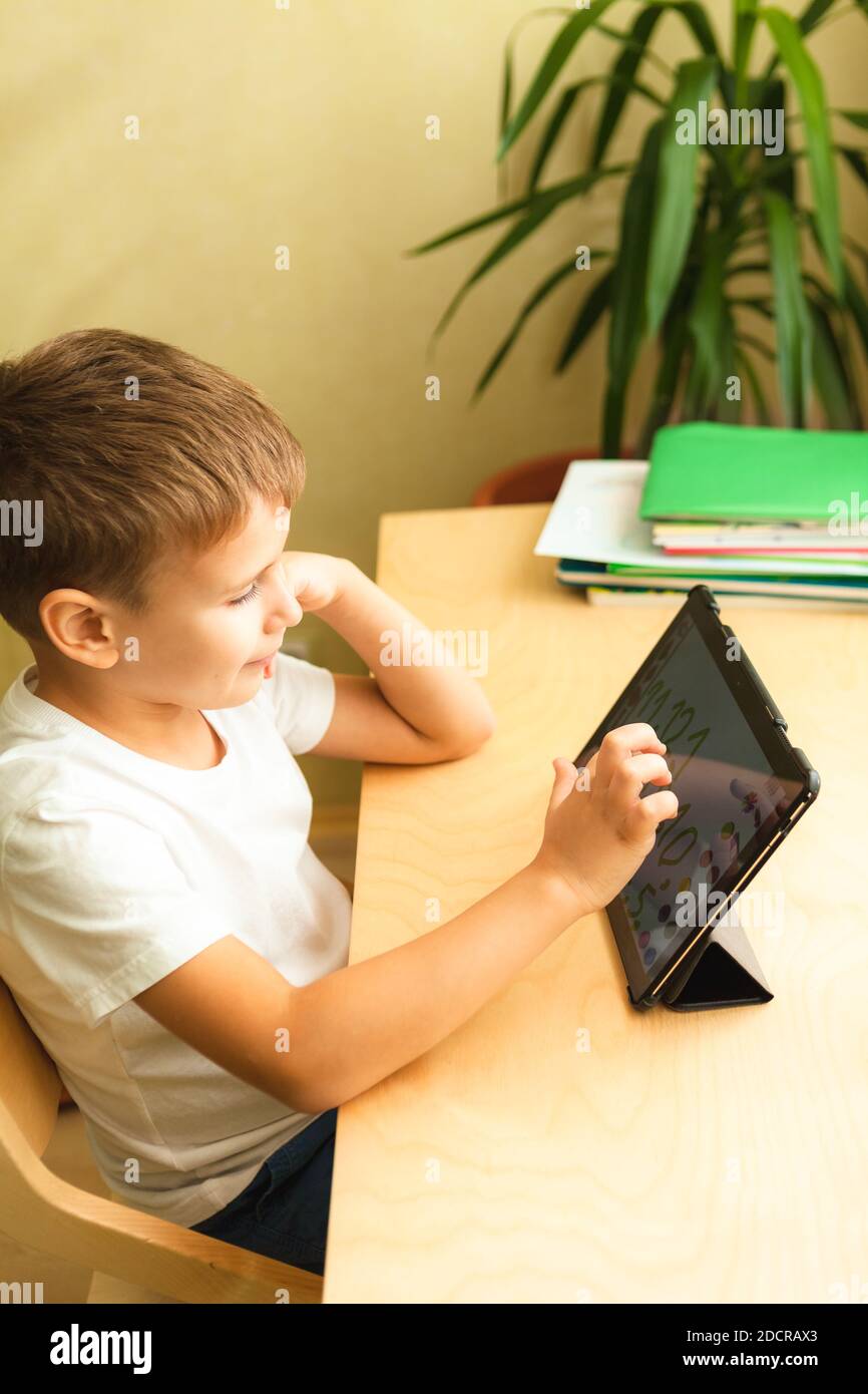 Happy boy doing homework with tablet at home. Child using gadgets for ...