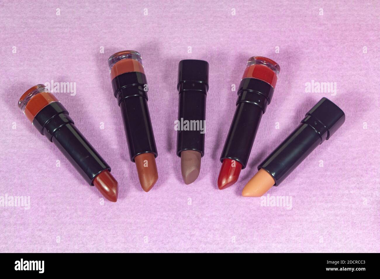 Different colors of lipsticks on purple background Stock Photo - Alamy