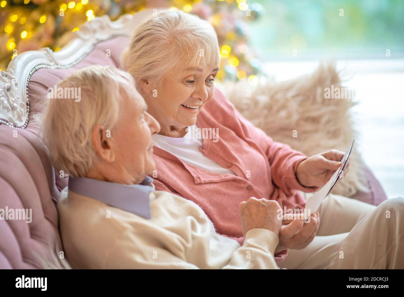 Elderly couple looking through old photographs and feeling nostalgic ...