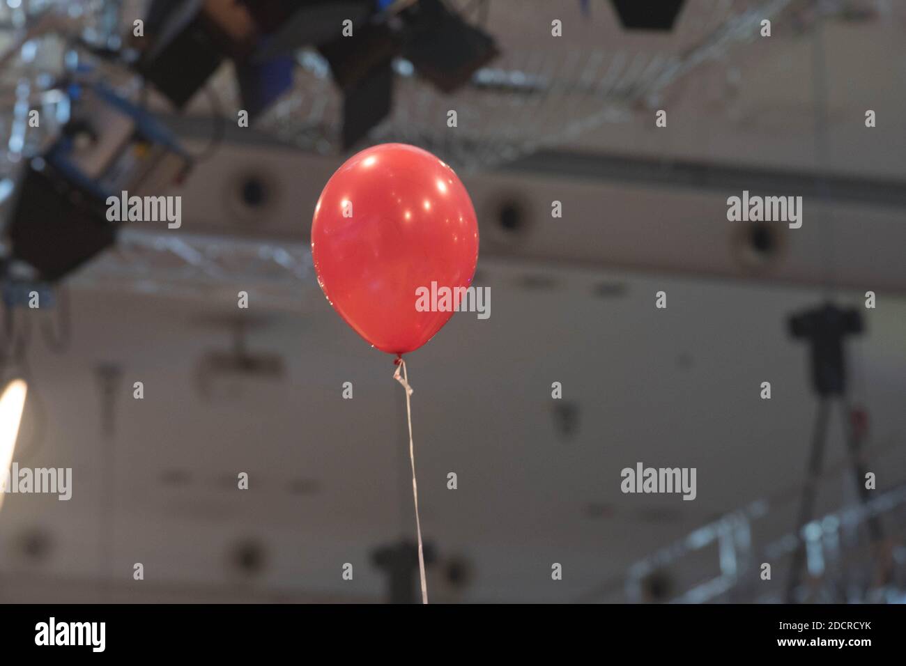 red balloon with a string attached, blurred ceiling in the background ...