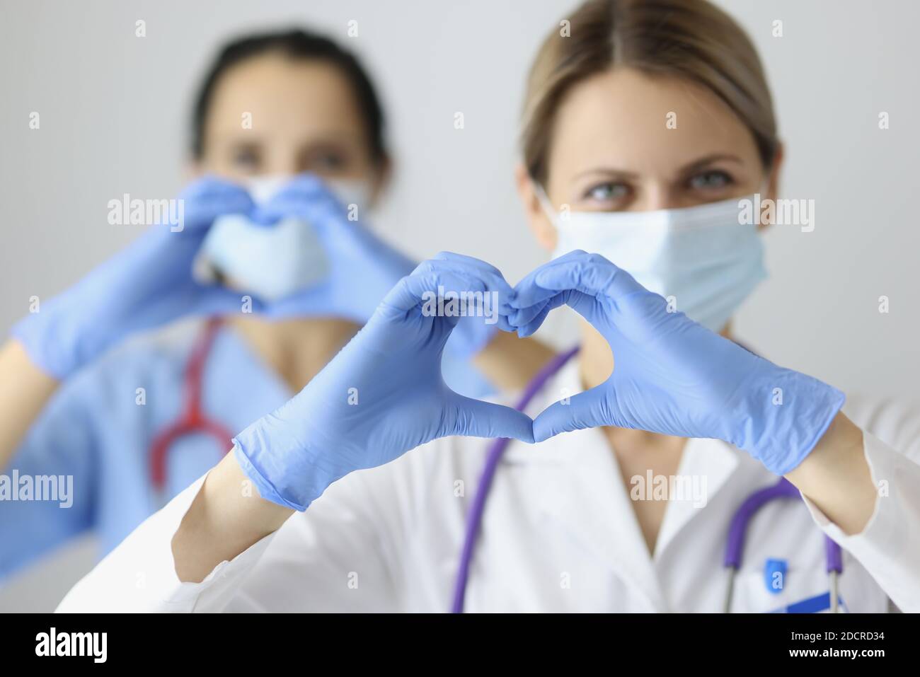 Two Doctor In Medical Masks And Rubber Gloves Showing Heart With Their