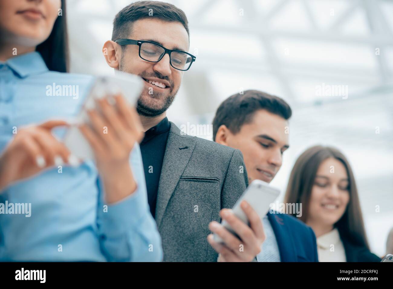 group of smiling business people looking at their smartphone screens ...