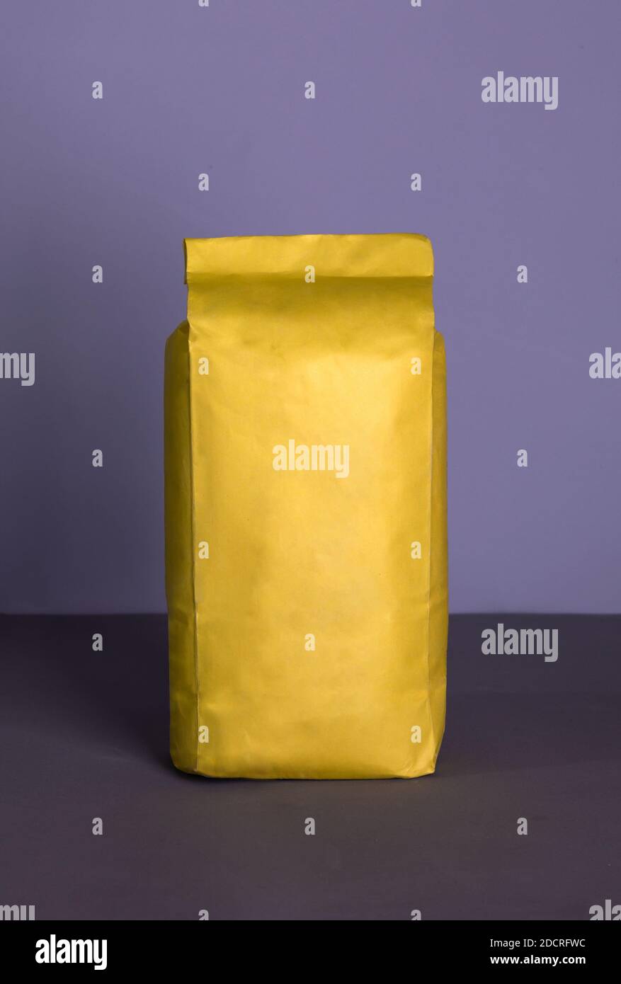 Small blank bulky yellow package with product on a purple-lilac ...
