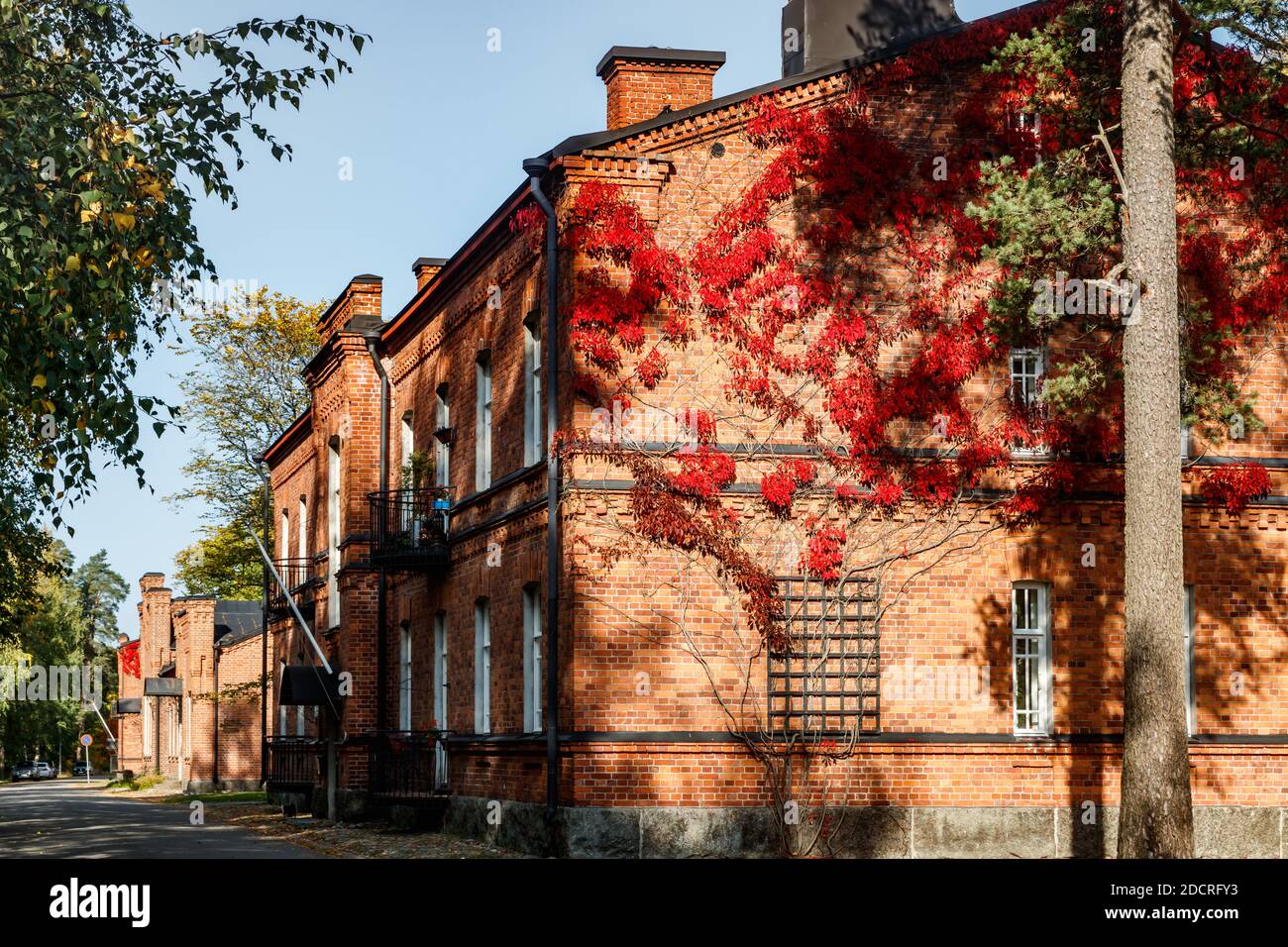 Autumnal view of red brick building covered by red foliage of ...