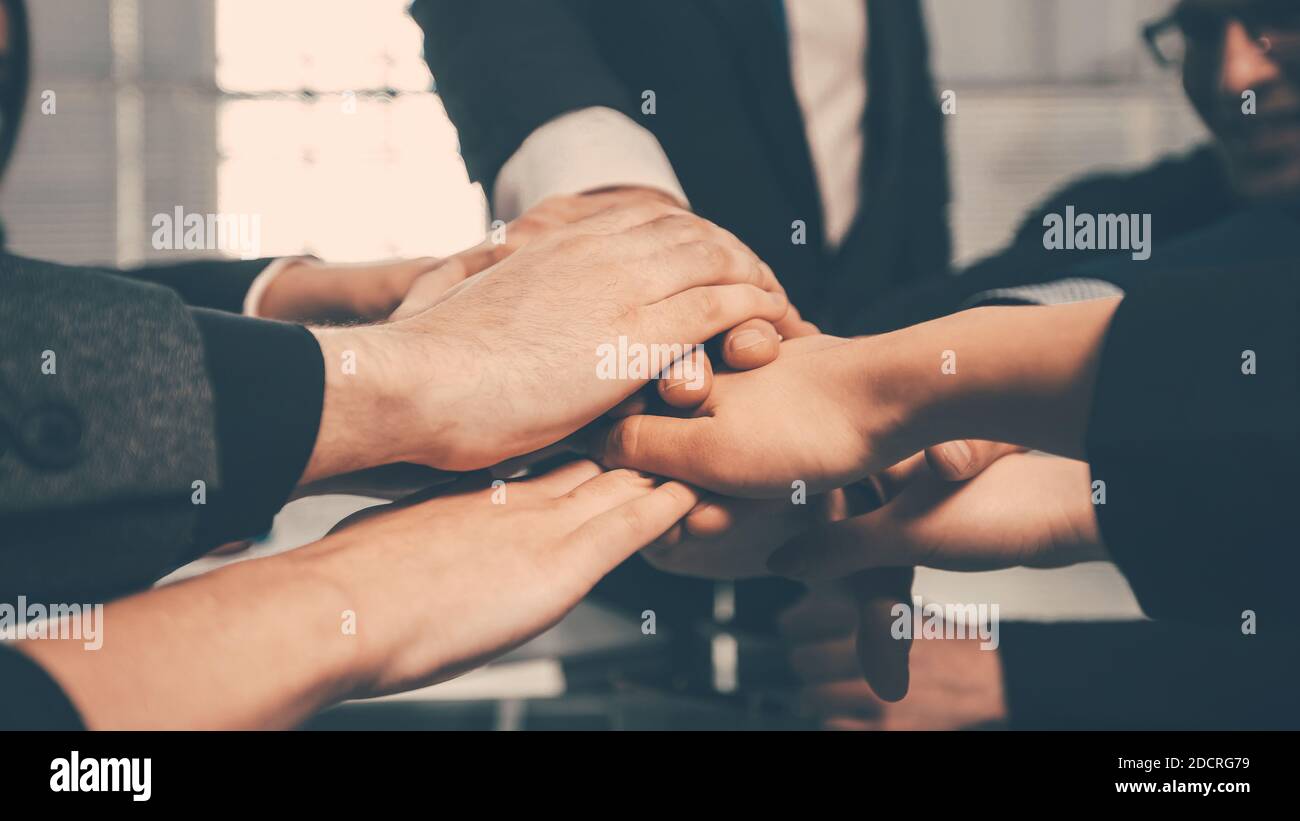 business team showing their unity while sitting at the office table ...