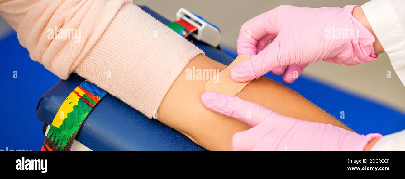 Close up of nurse hand applying adhesive plaster on arm of patient ...