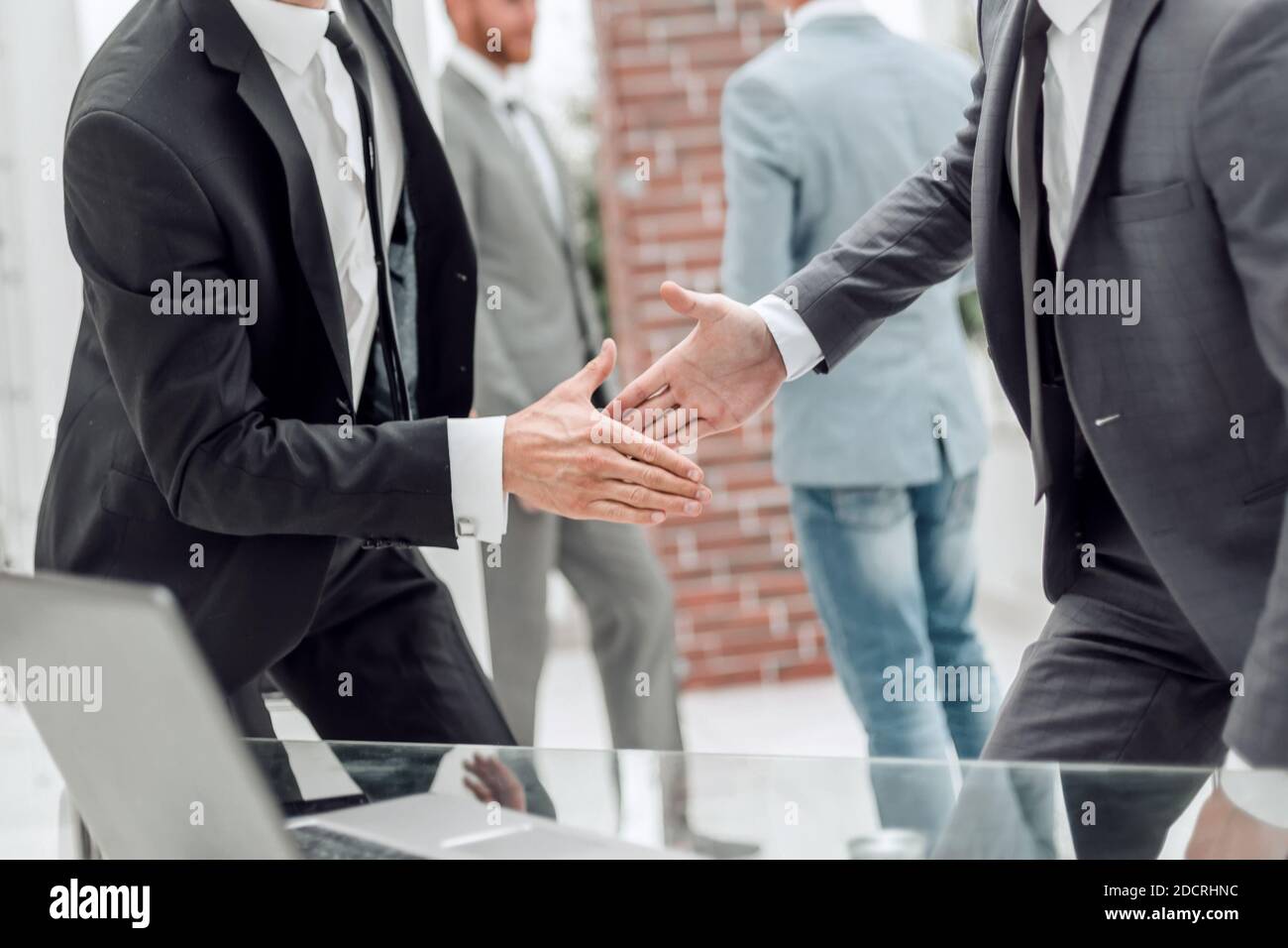 happy business people shaking hands near the desktop Stock Photo - Alamy