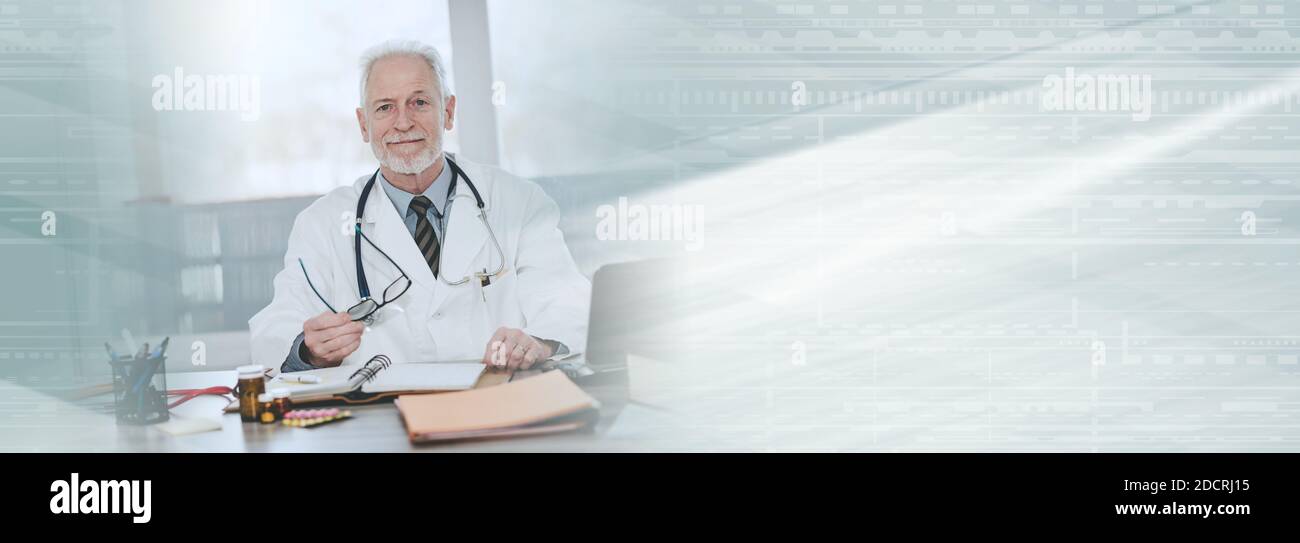 Portrait of male senior doctor sitting in medical office; panoramic ...
