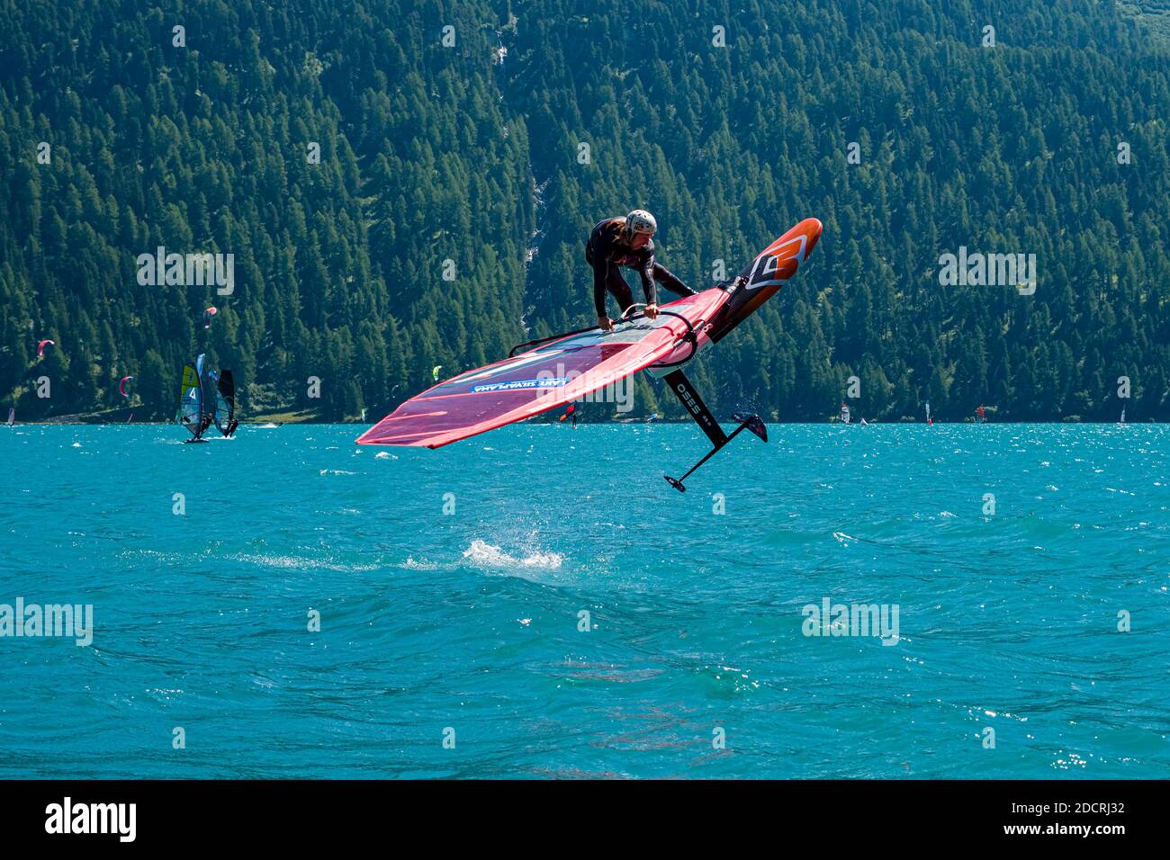 A wind surfer with red sail is jumping on Lake Silvaplana Stock Photo ...