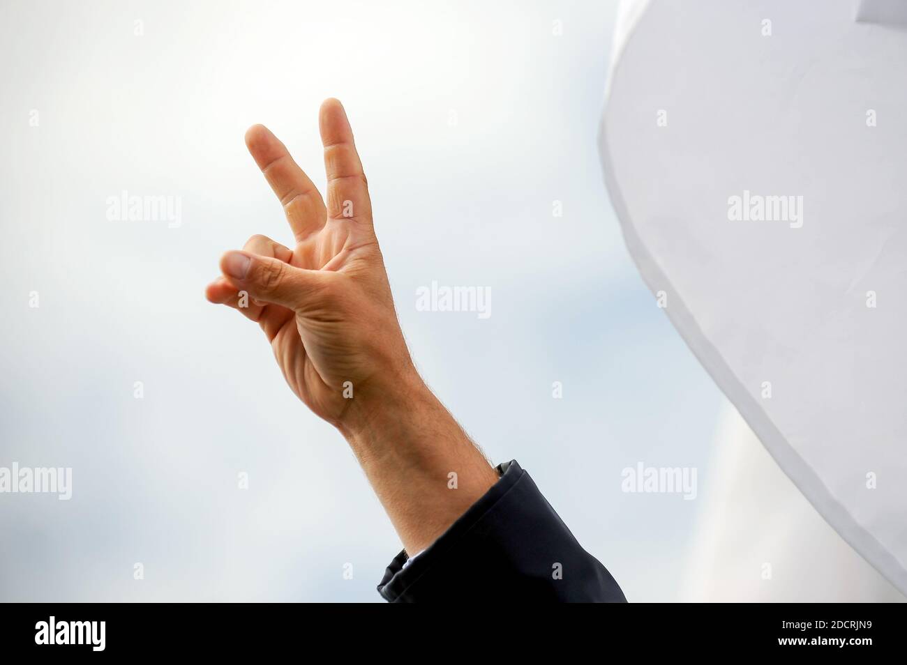 Details with the hand of a protestor showing the victory sign during a ...