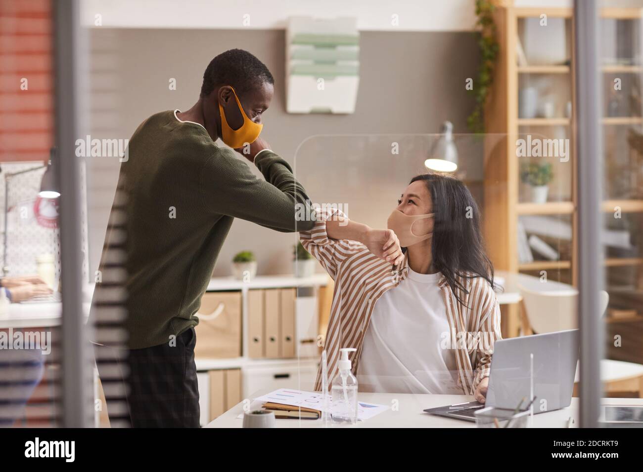 Portrait of two colleagues touching elbows as contactless greeting in ...
