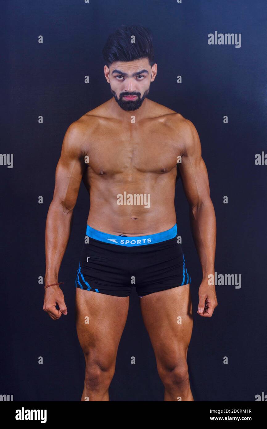 Muscular bodybuilder male in gym. Black background. Front profile ...