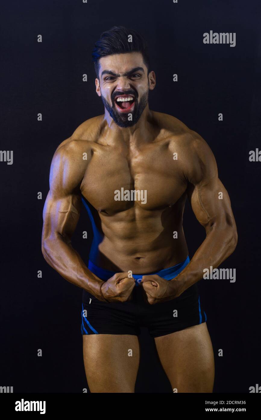 Muscular bodybuilder male in gym. Black background. Front profile ...