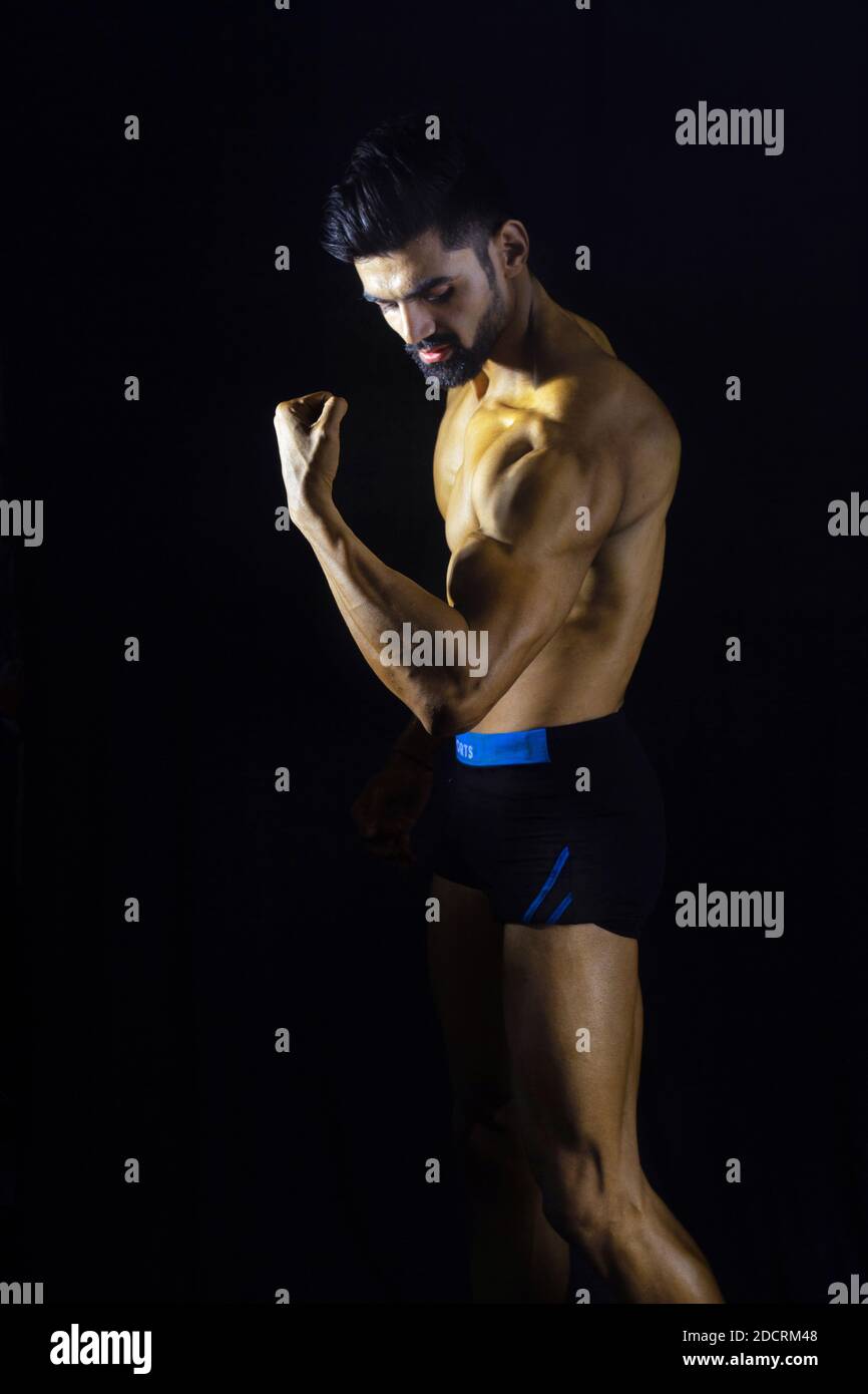 Muscular bodybuilder male in gym. Black background. side profile ...