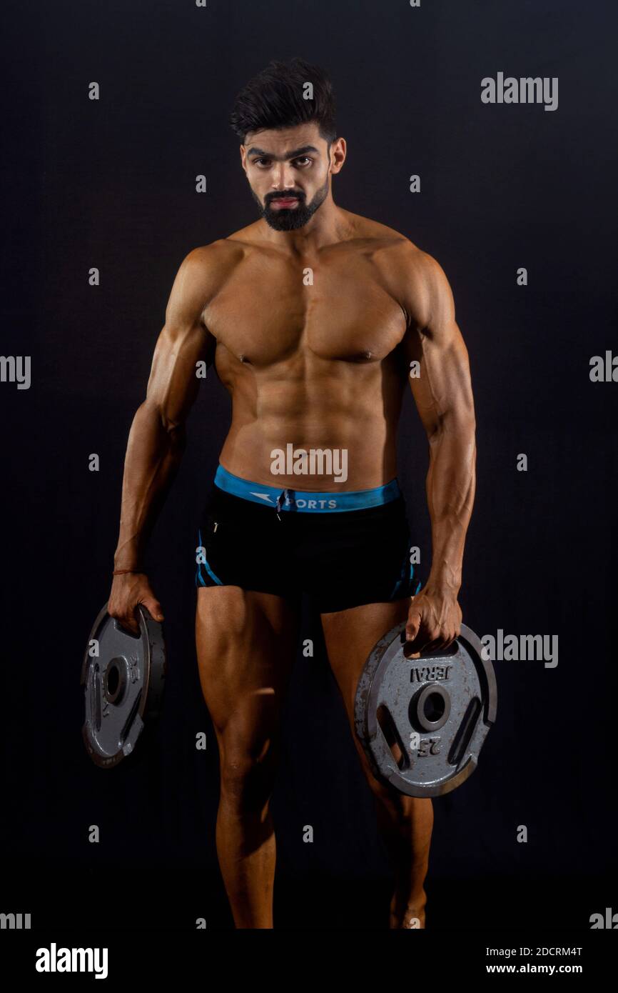 Muscular bodybuilder male in gym. Black background. Front profile ...