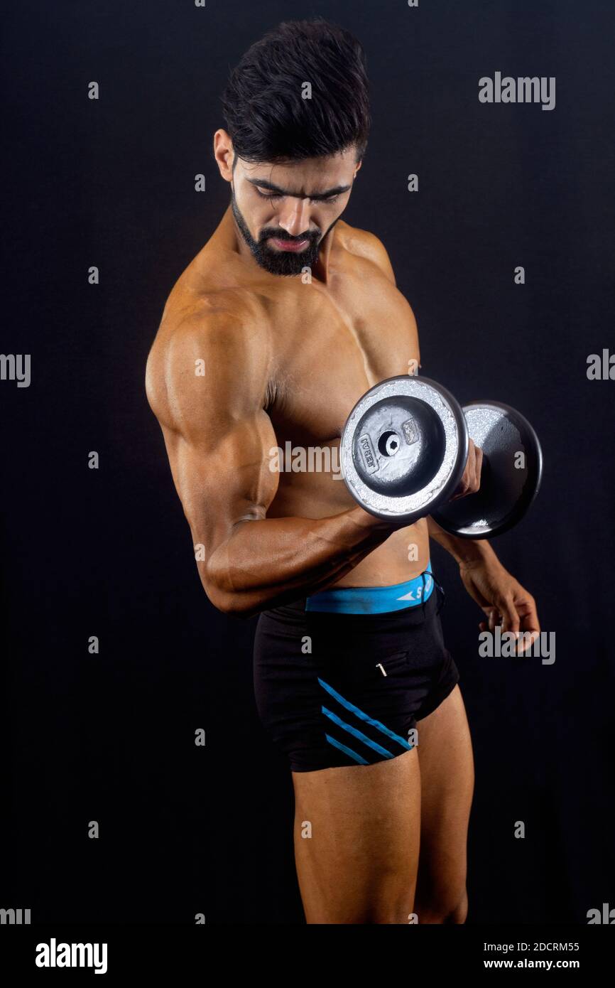 Muscular bodybuilder male in gym. Black background. Front profile ...