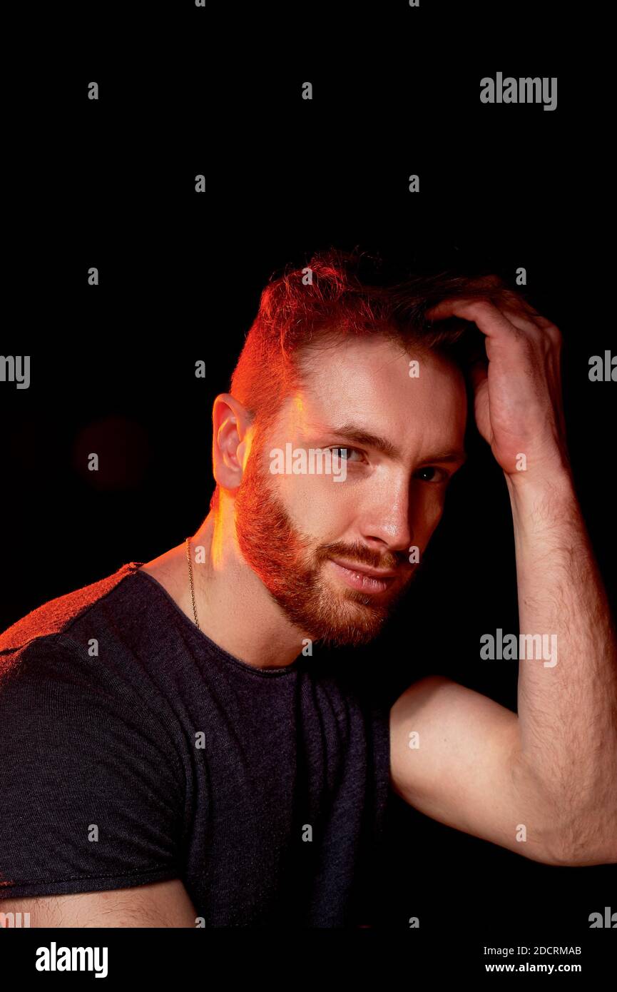 A brutal man on a dark background in the light of a red lamp Stock ...