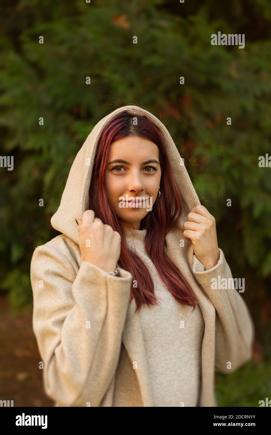 A vertical shot of a beautiful Caucasian girl wearing a coat in a park ...