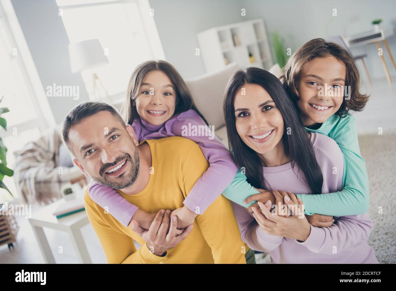 Photo of full family four people parents hold piggy back kids wear ...
