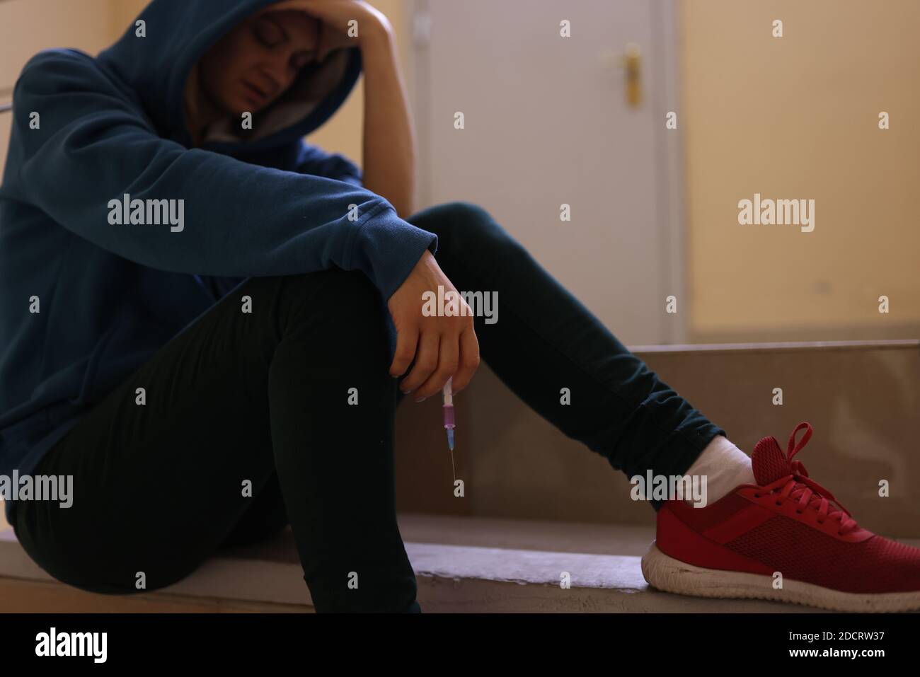 Addict sits with his head down and holds syringe in his hands Stock ...