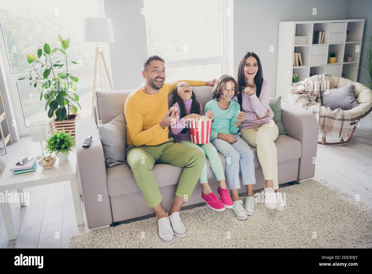 Photo of full family four people sit couch eat pop corn watch tv laugh ...