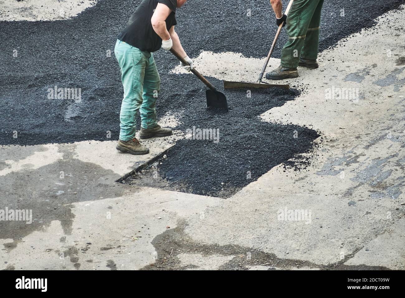 workers are repairing the road. paving of asphalt by man. man throwing ...