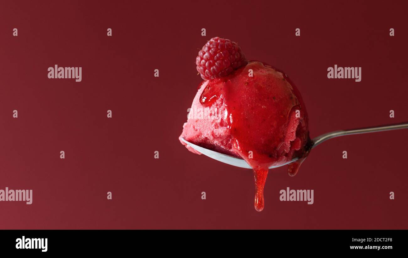 A scoop of raspberry ice cream with melting raspberry topping on top ...