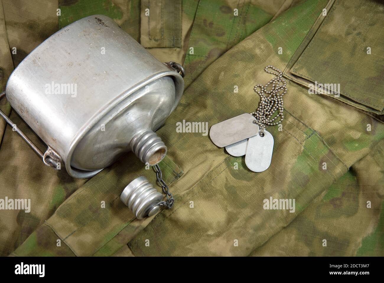 a soldier's water bottle lies on camouflage with soldier badge on a ...