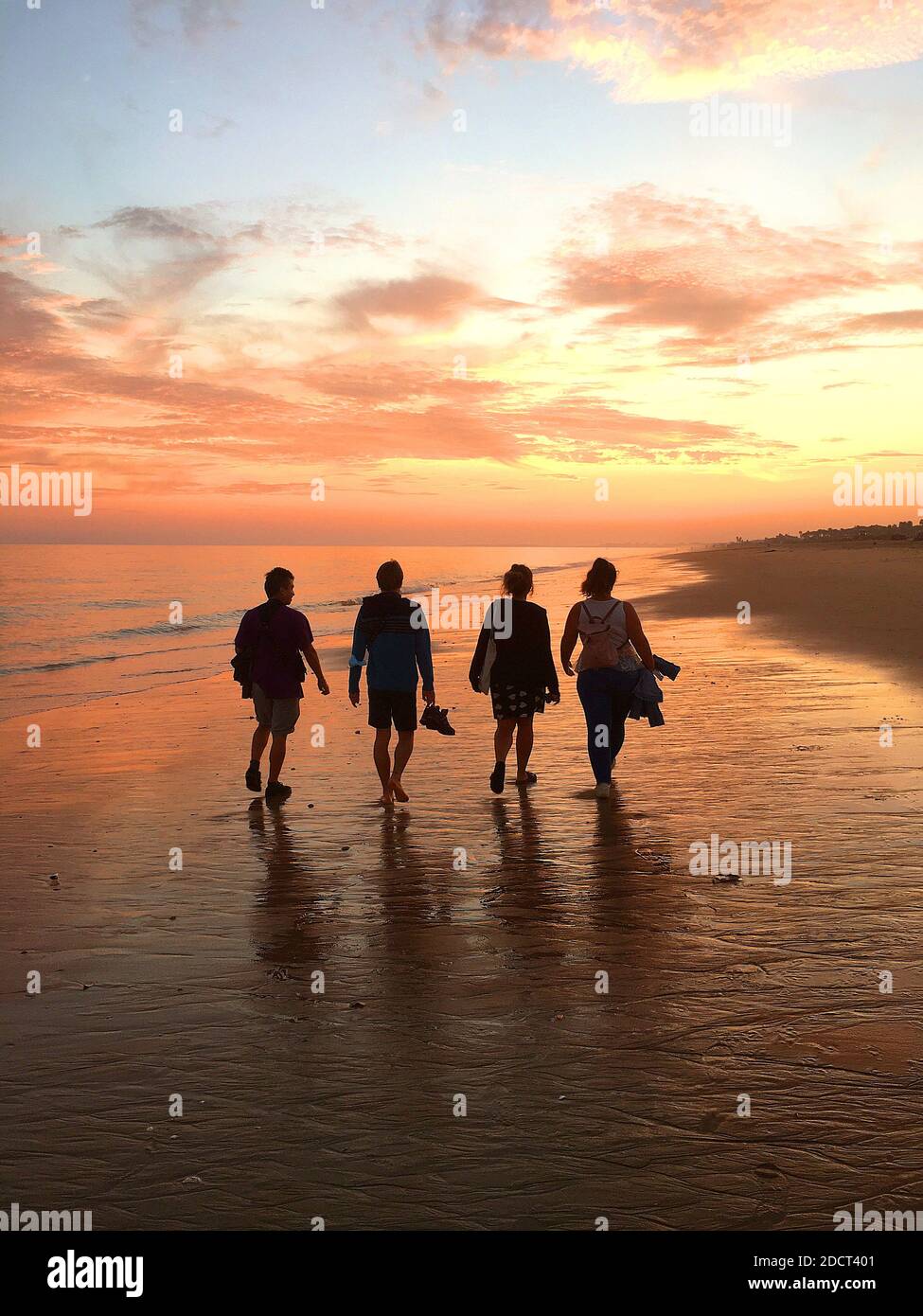 Group of friends walking at the beach during sunset Stock Photo - Alamy