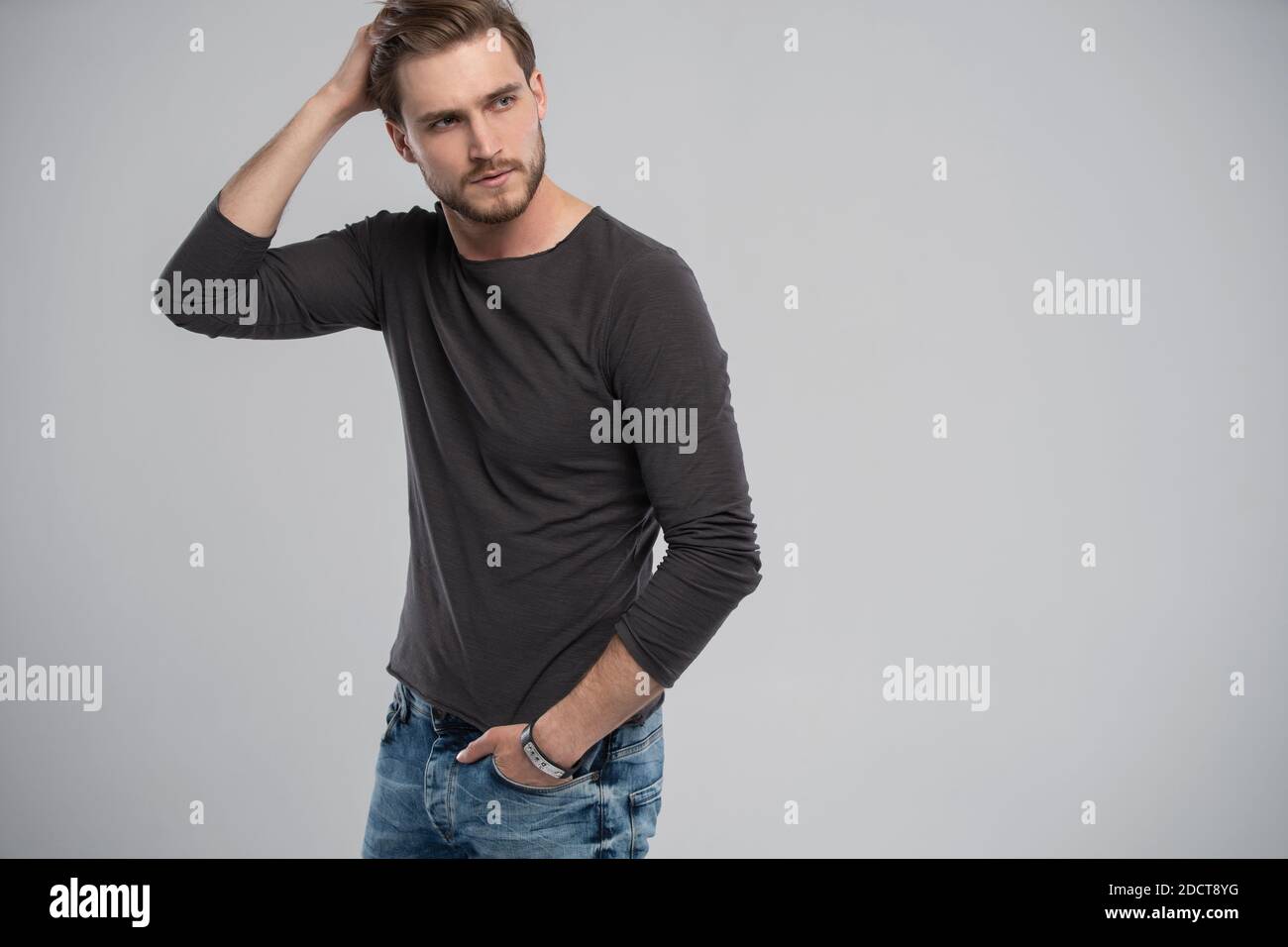 Portrait of a smart young man standing against grey background Stock ...