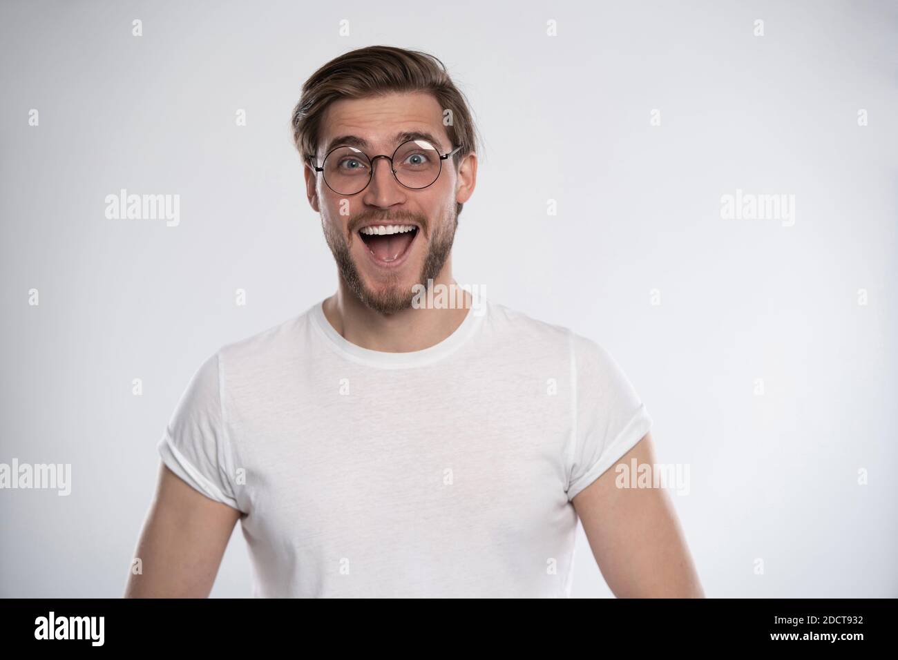 Attractive young bearded man looks with astonishment into camera, being ...